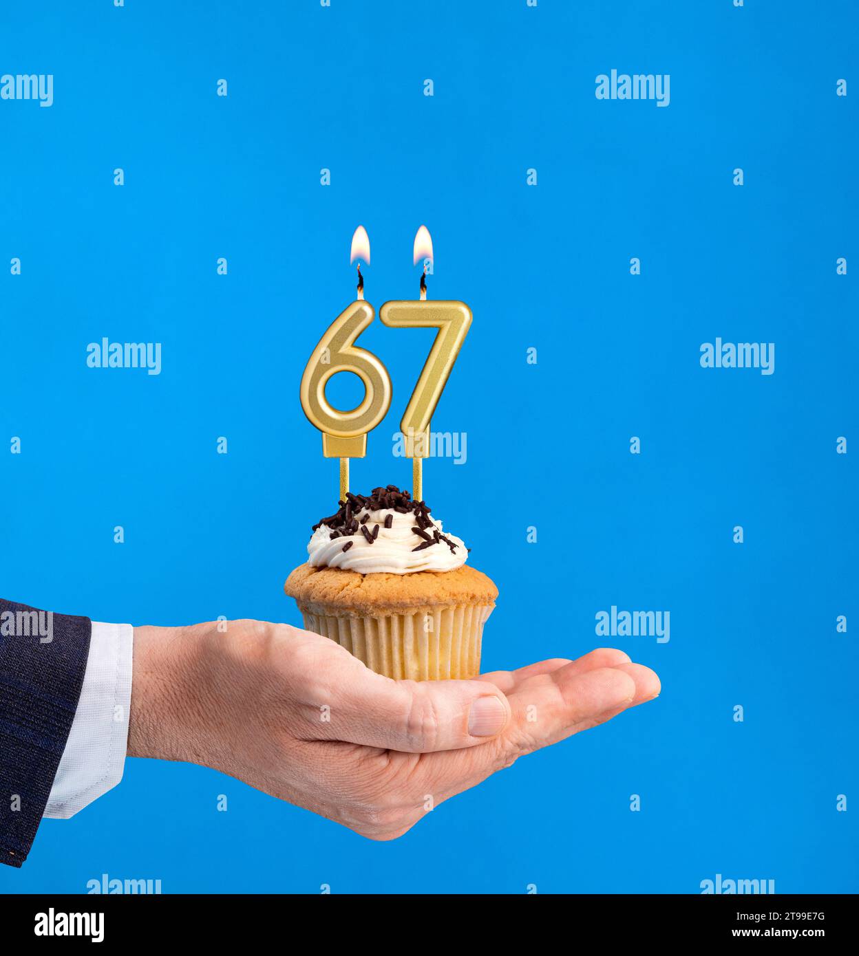 Hand holding a cupcake with the number 67 candle - Birthday on blue ...