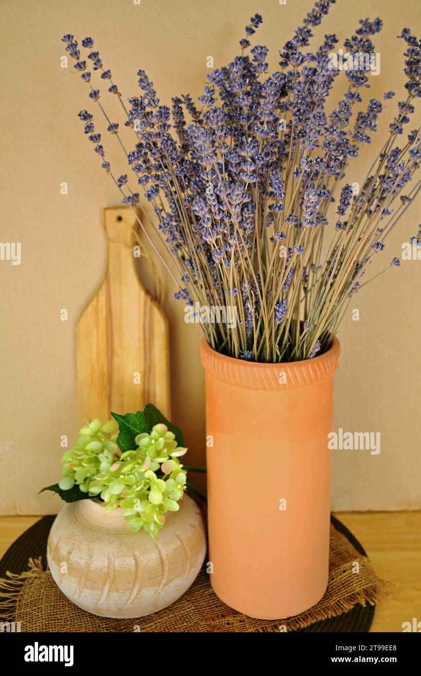 Fragrant dried lavender and hydrangeas in clay vases with wooden cheese ...