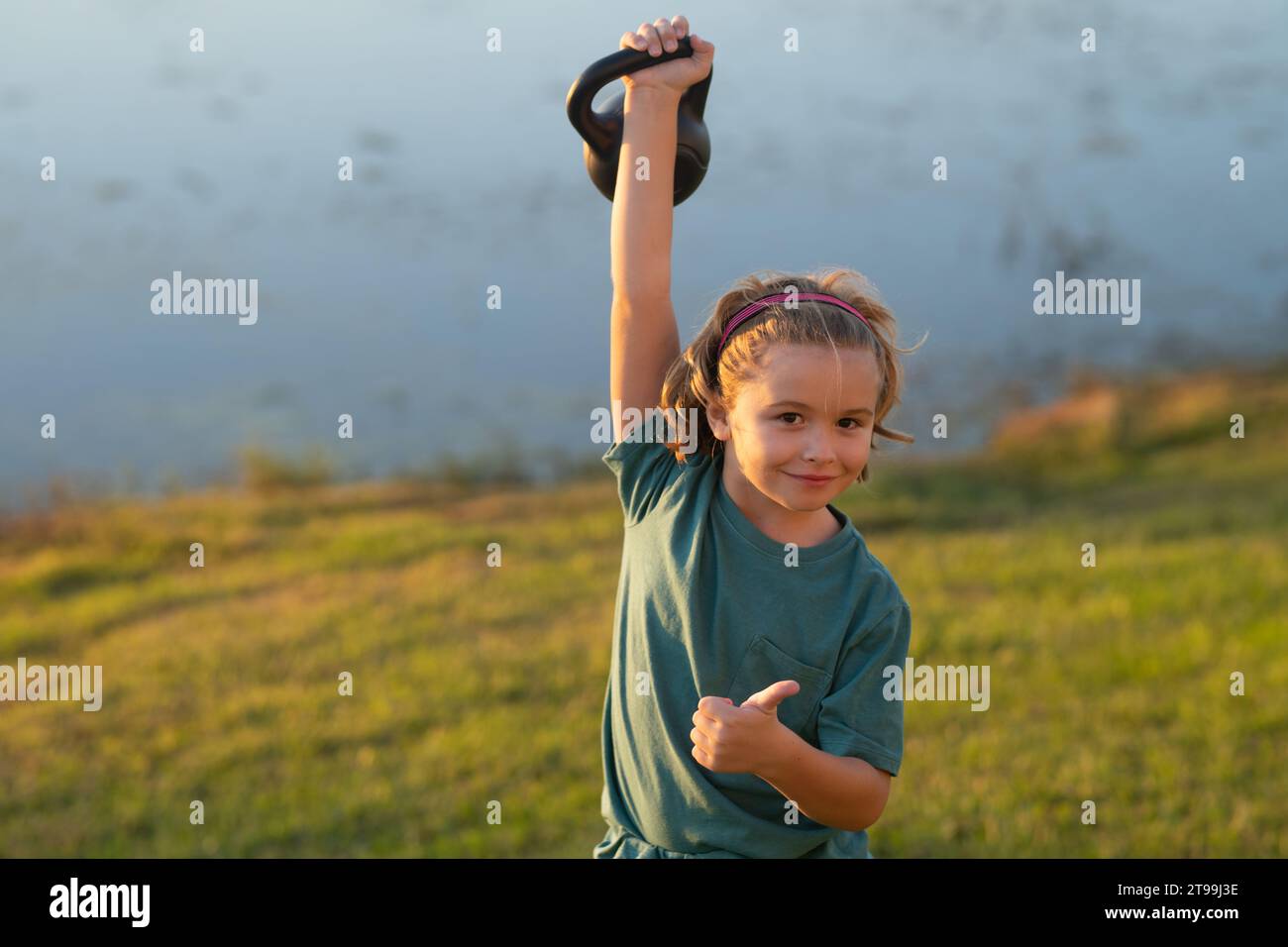 Child lifting the kettlebell in backyard outside. Kids sports exercises ...