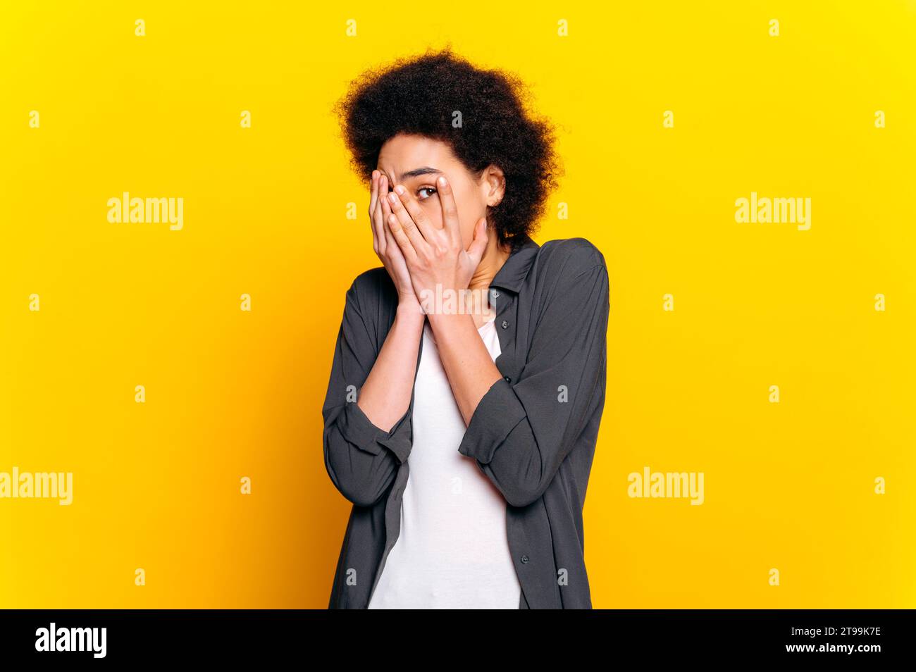 Terrified african american curly haired woman dressed in casual shirt ...