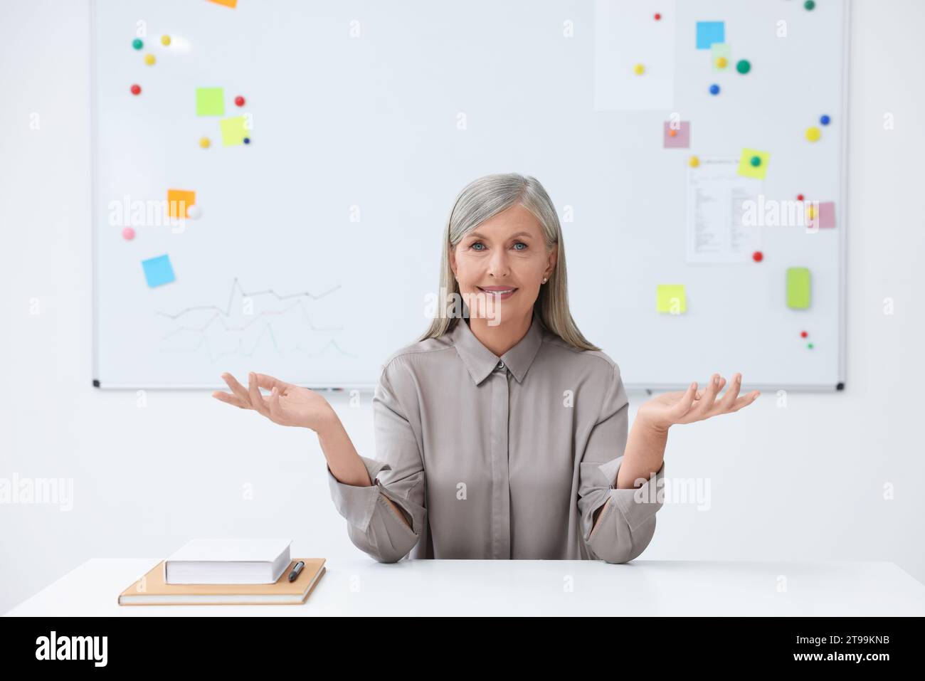 Happy professor giving lecture at desk in classroom Stock Photo - Alamy