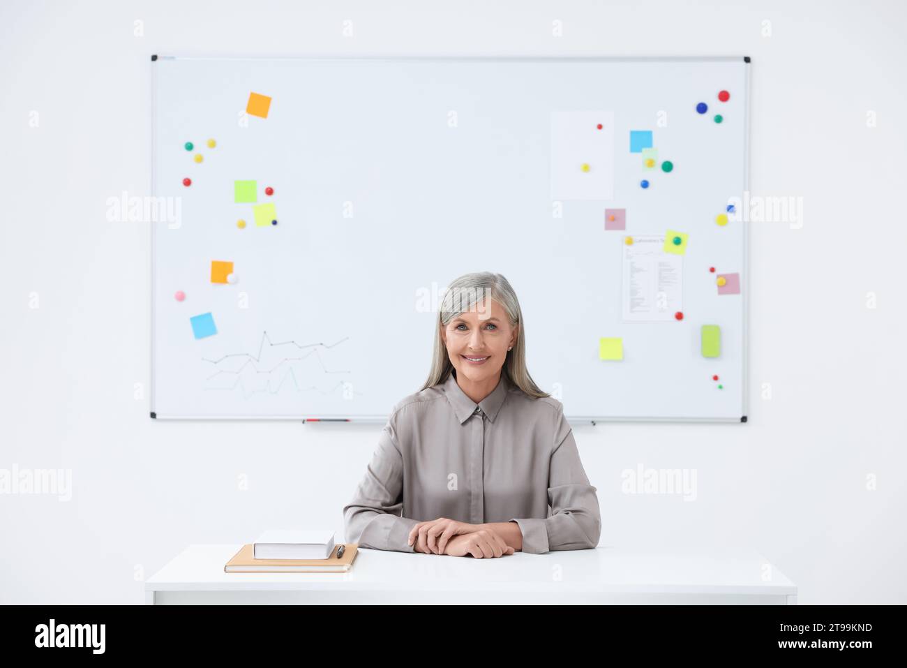 Portrait of professor sitting at desk in classroom Stock Photo - Alamy