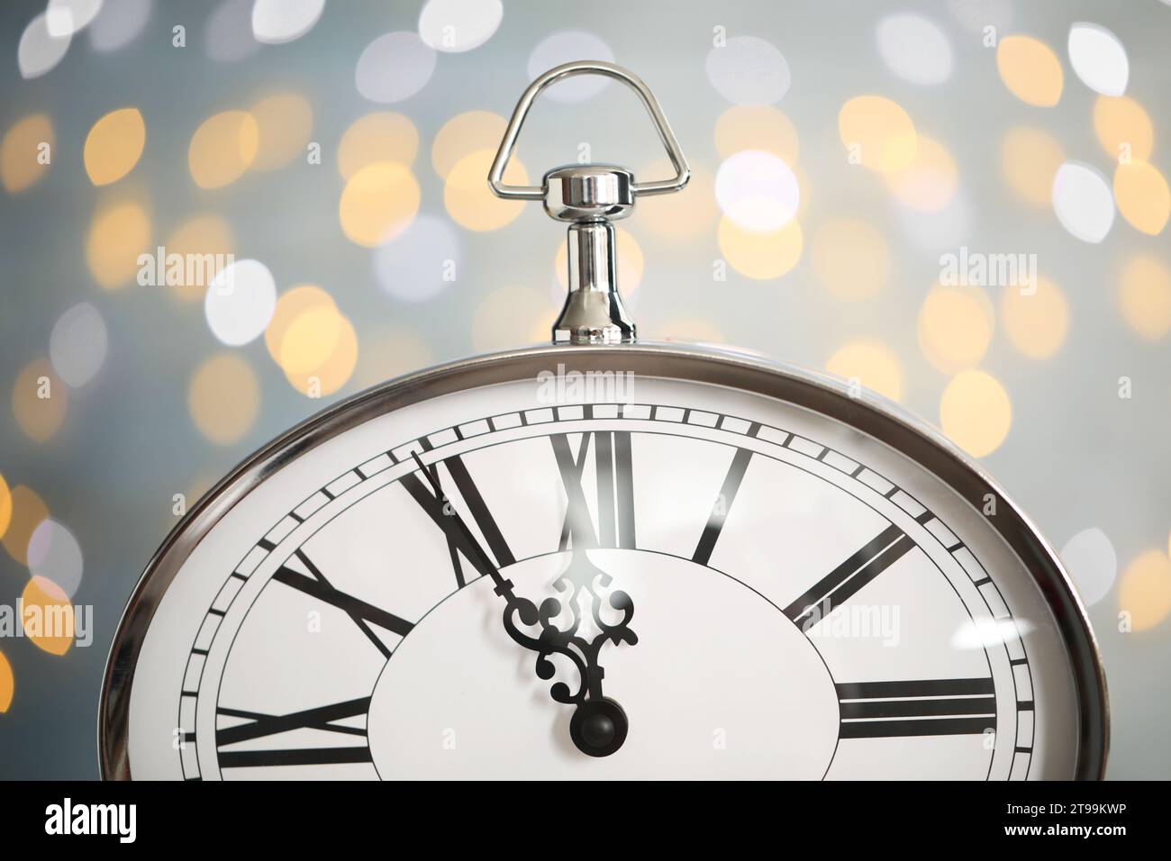 Clock showing five minutes until midnight on blurred background ...