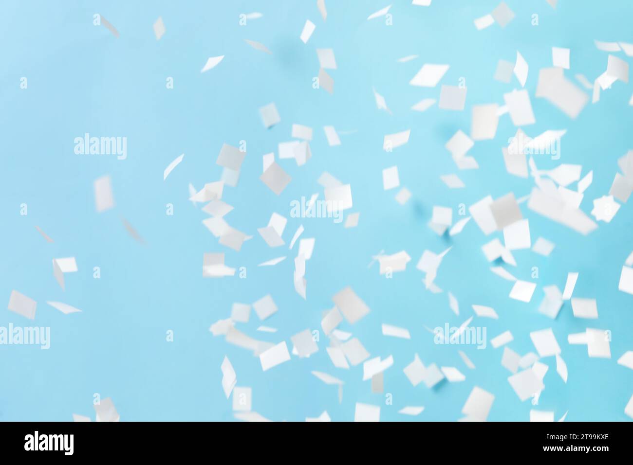 White confetti falling down on light blue background Stock Photo - Alamy