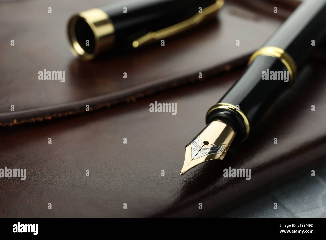 Stylish fountain pen, cap and leather notebook on grey table, closeup ...