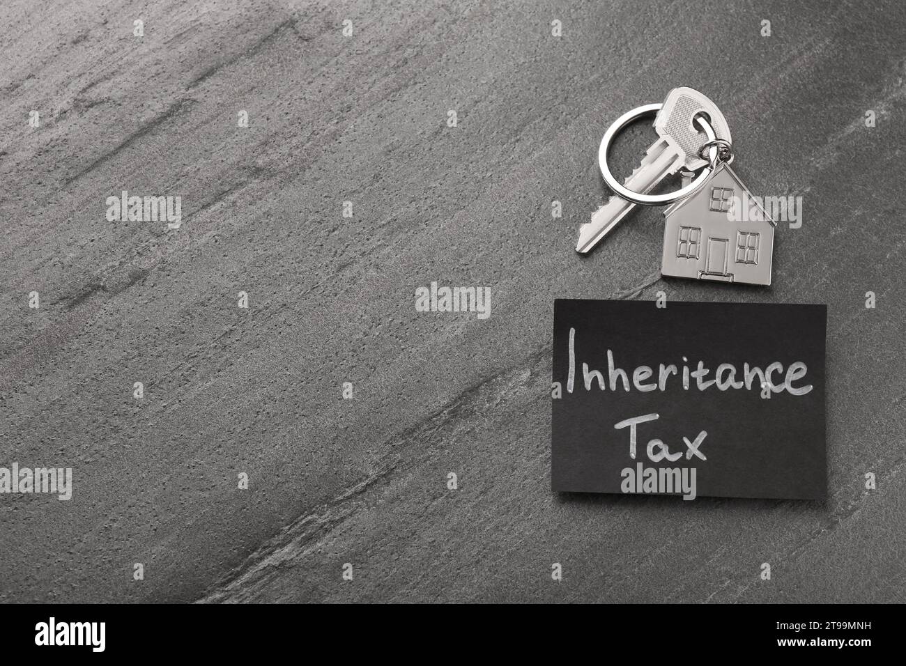 Inheritance Tax. Card and key with key chain in shape of house on grey ... Inheritance Tax. Card and key with key chain in shape of house on grey ...