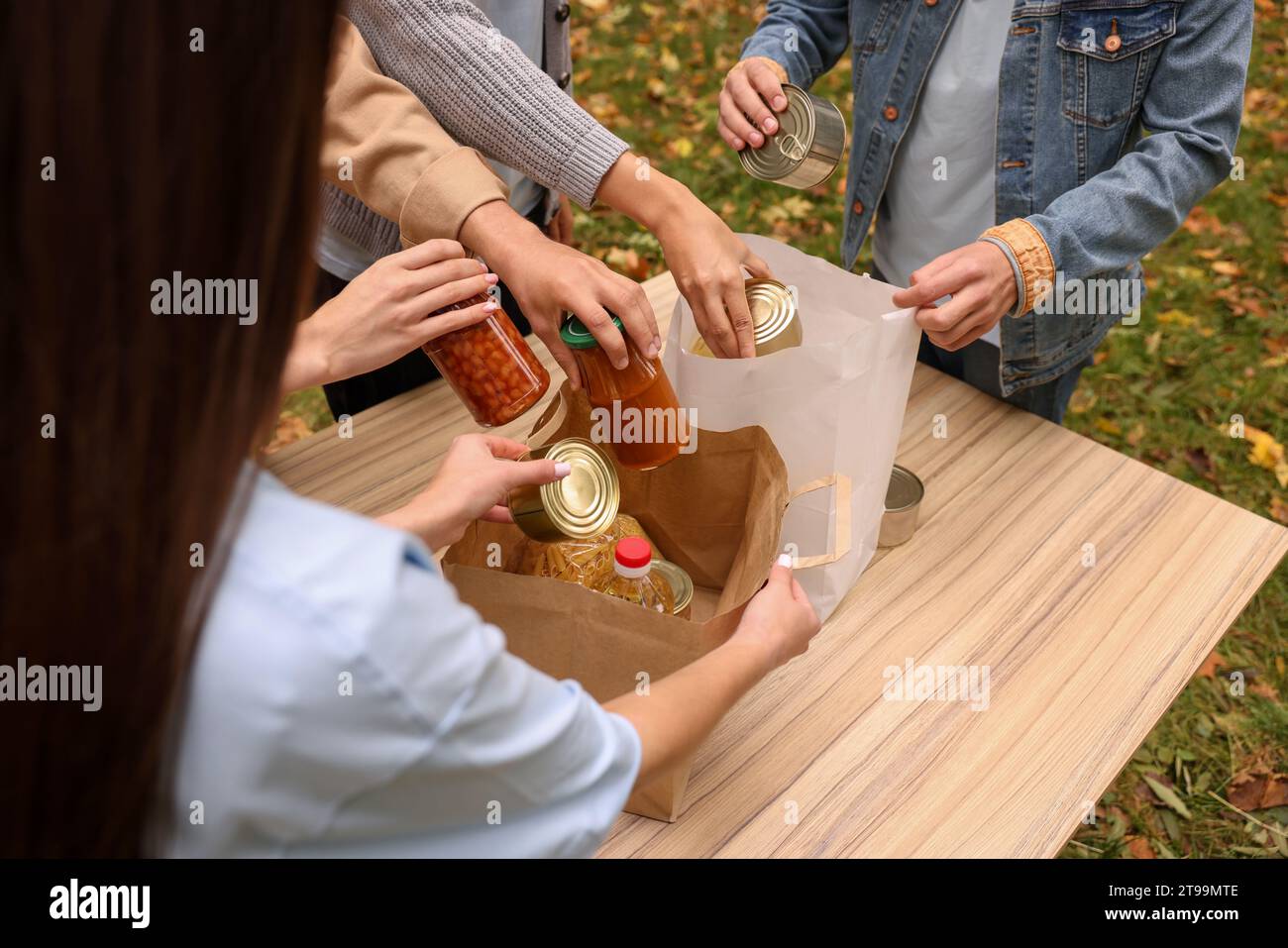 Group of volunteers packing food products at table outdoors, closeup ...