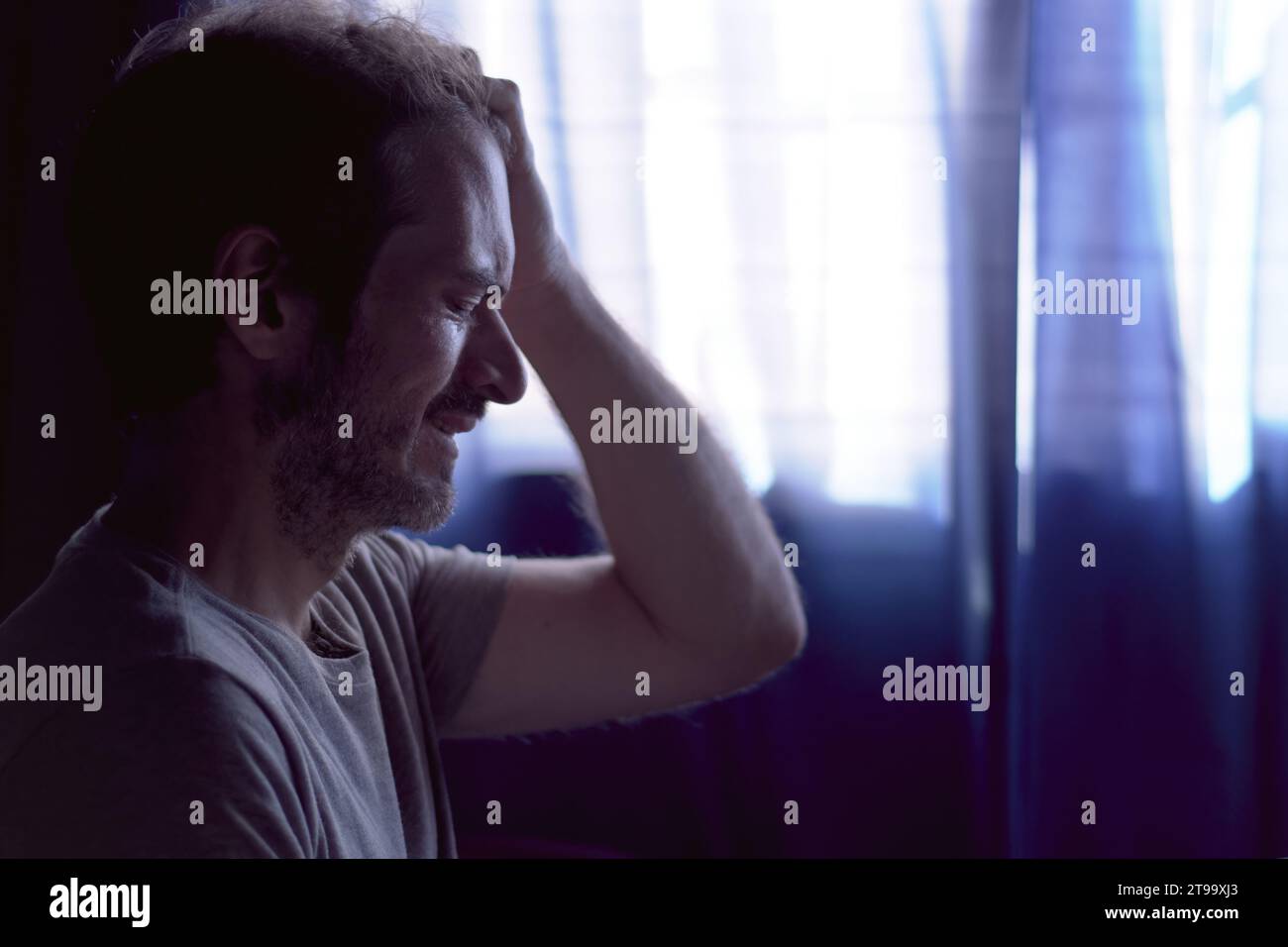 Depressed young bearded man crying with closed eyes and his hand on his ...