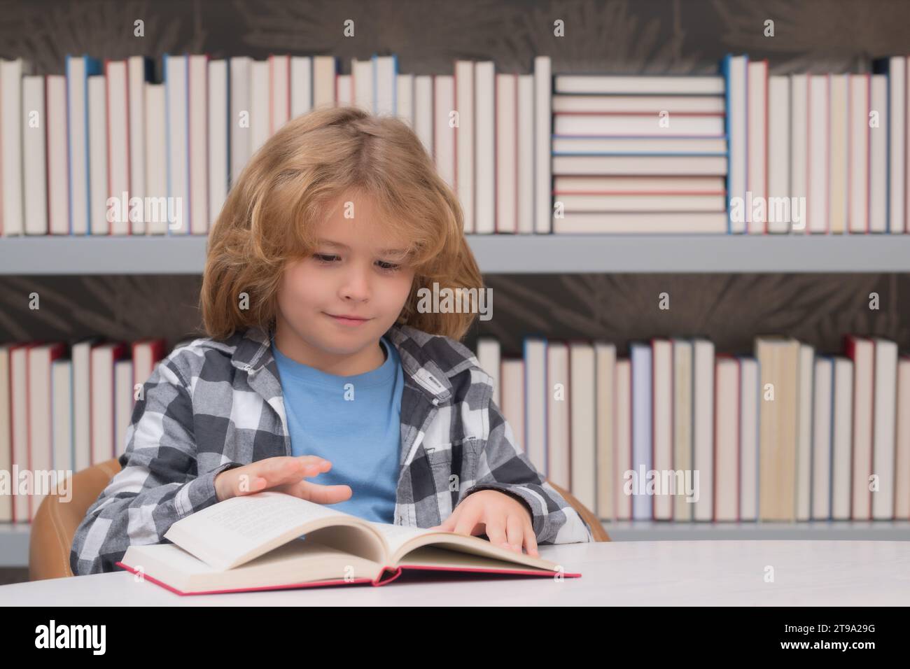 Cute school kid studying in school library. Portrait of child reading ...