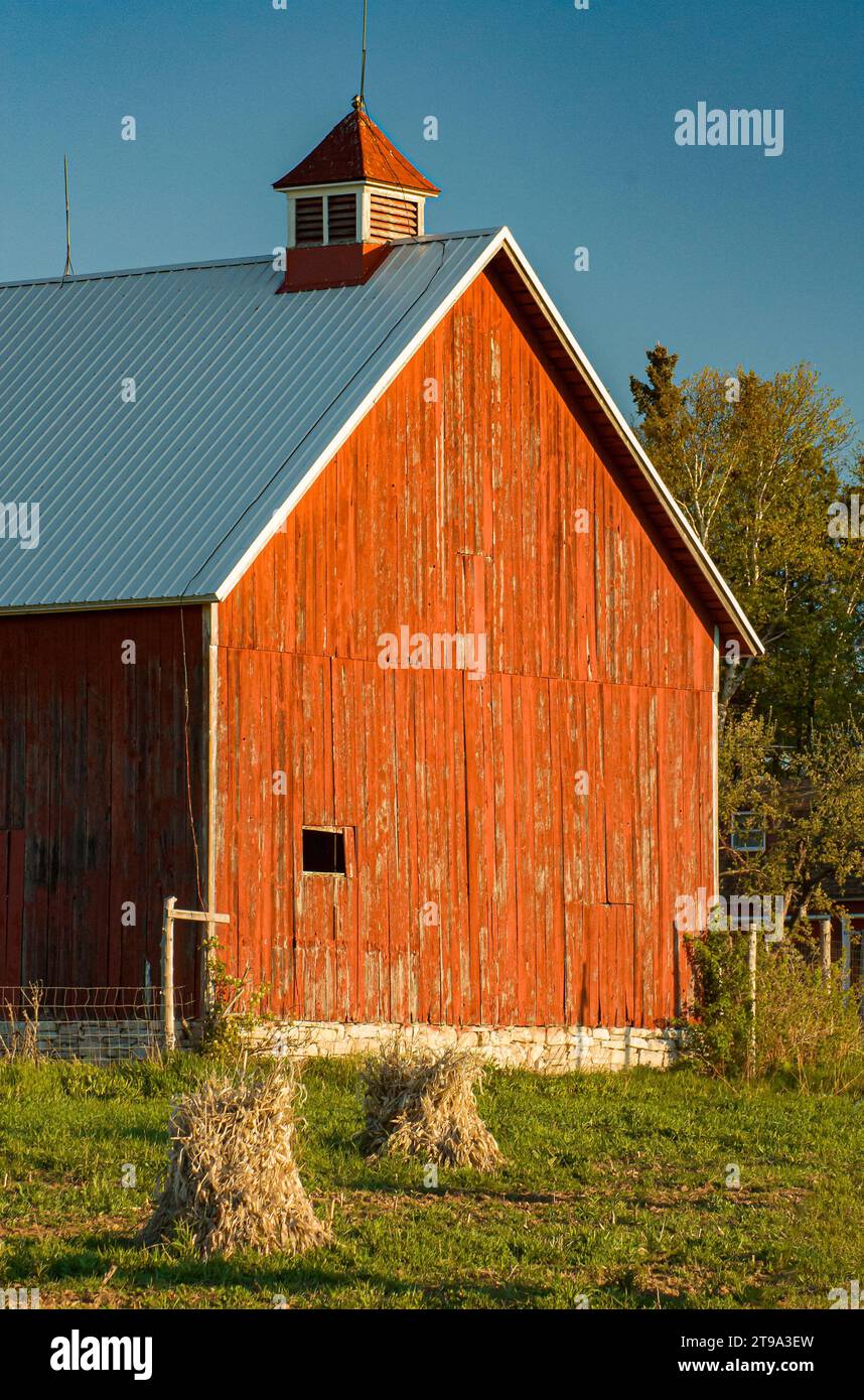 A small window is framed by a couple haystacks on the side of a barn in ...