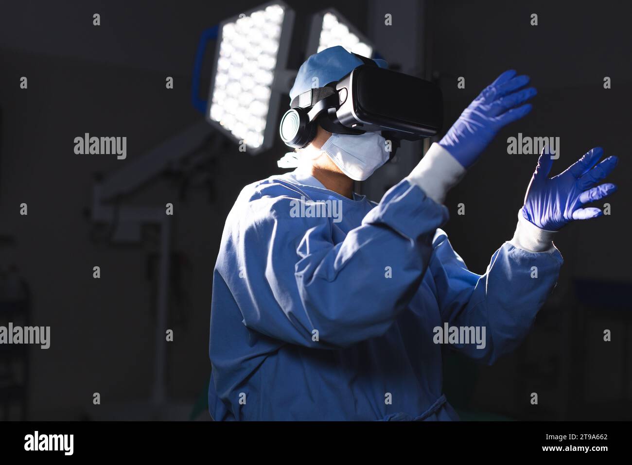 Biracial female surgeon wearing surgical gown using vr headset in ...