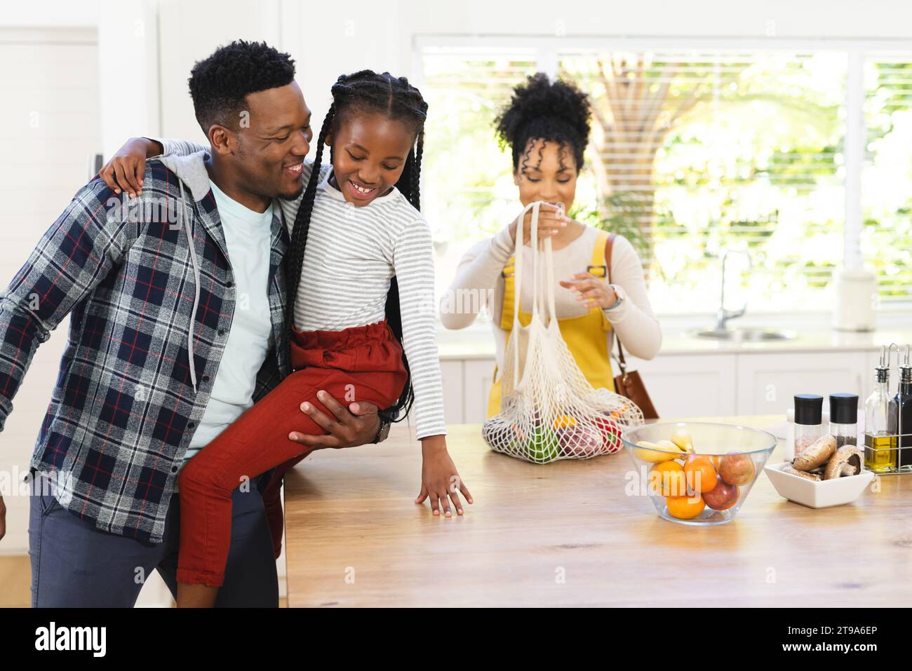 Happy african american family putting groceries on table in kitchen at ...