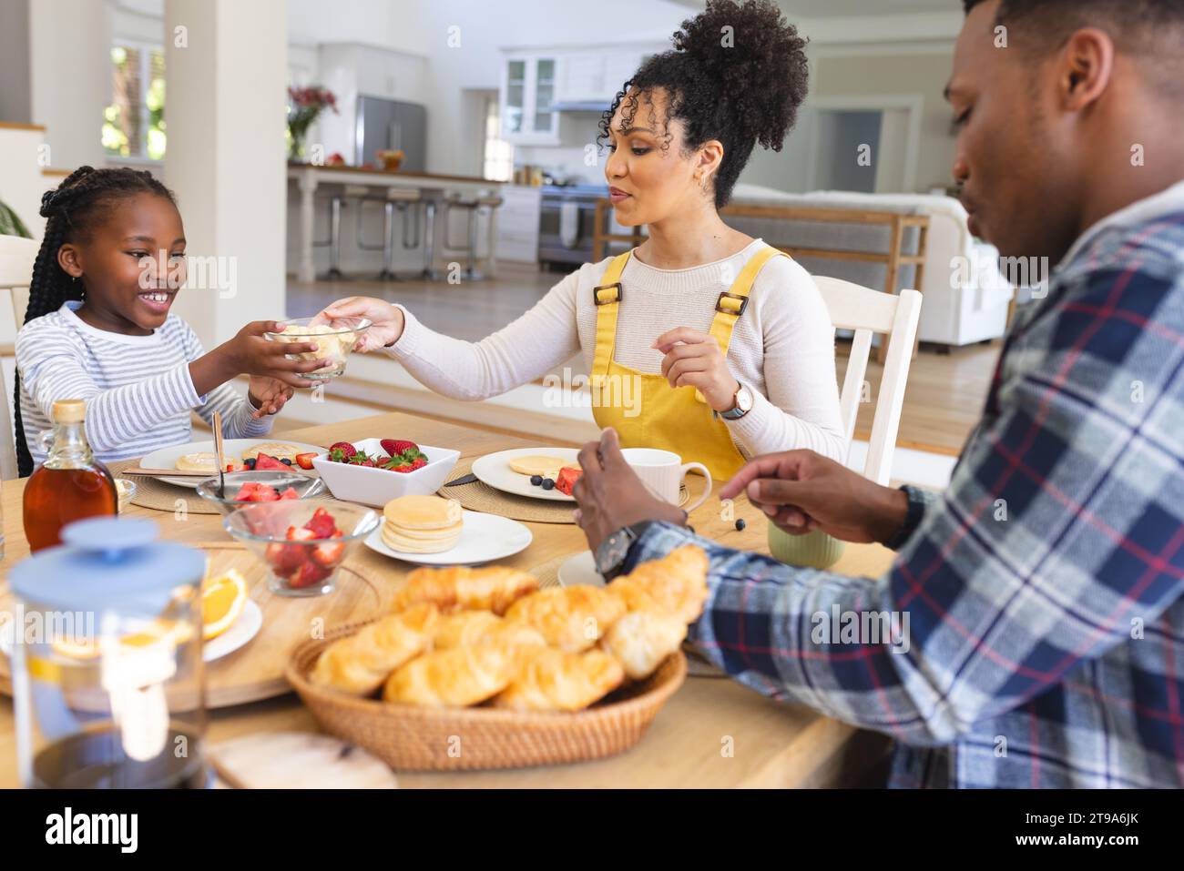 Happy african american family having fresh fruits snack in dining room at home, copy space ...