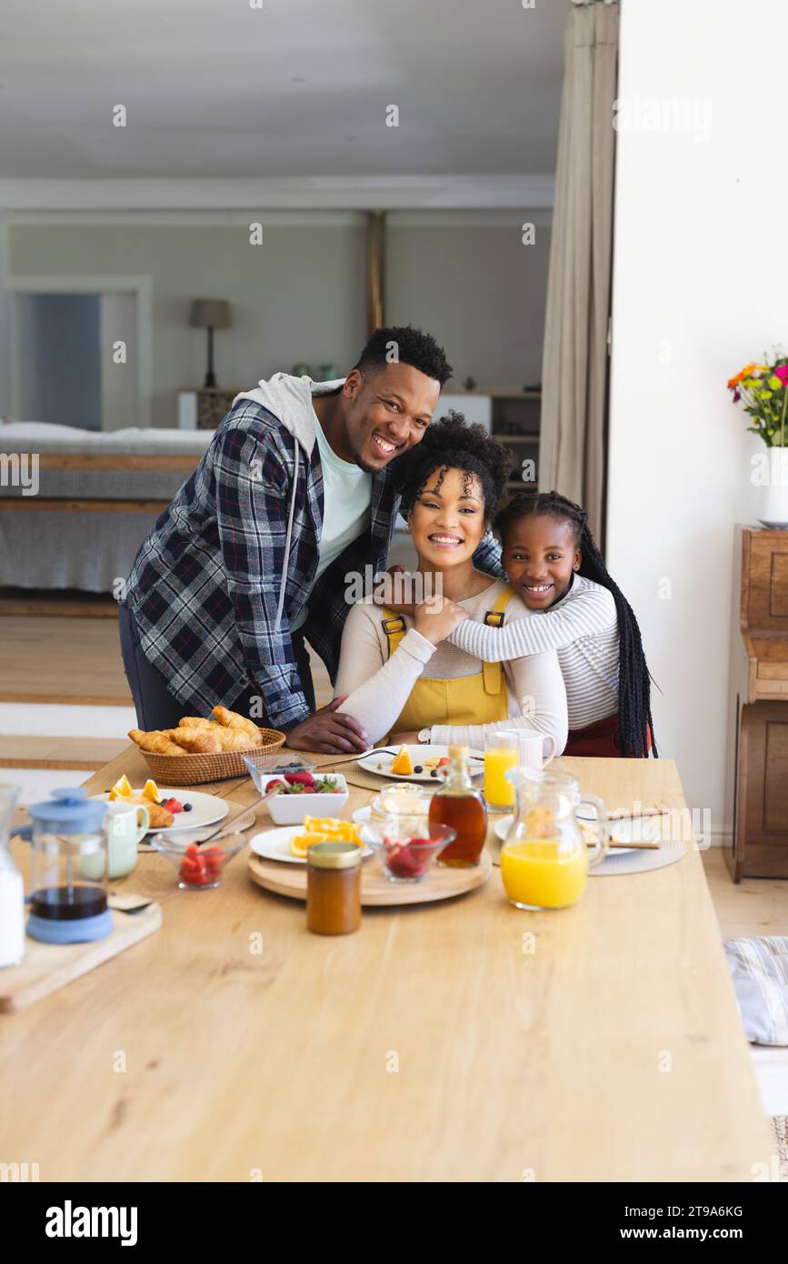 Portrait of happy african american family embracing at table in dining room at home, copy space ...