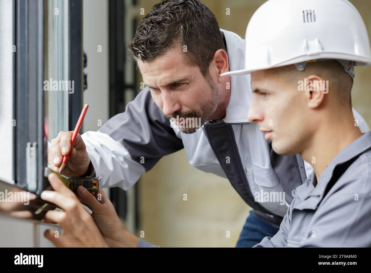 assisting window installation apprentice in measuring the window Stock ...