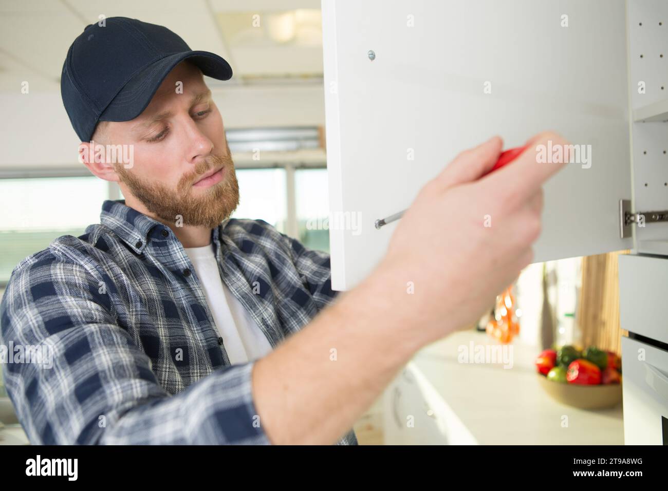 man using screwdriver to install a kitchen cupboard Stock Photo - Alamy