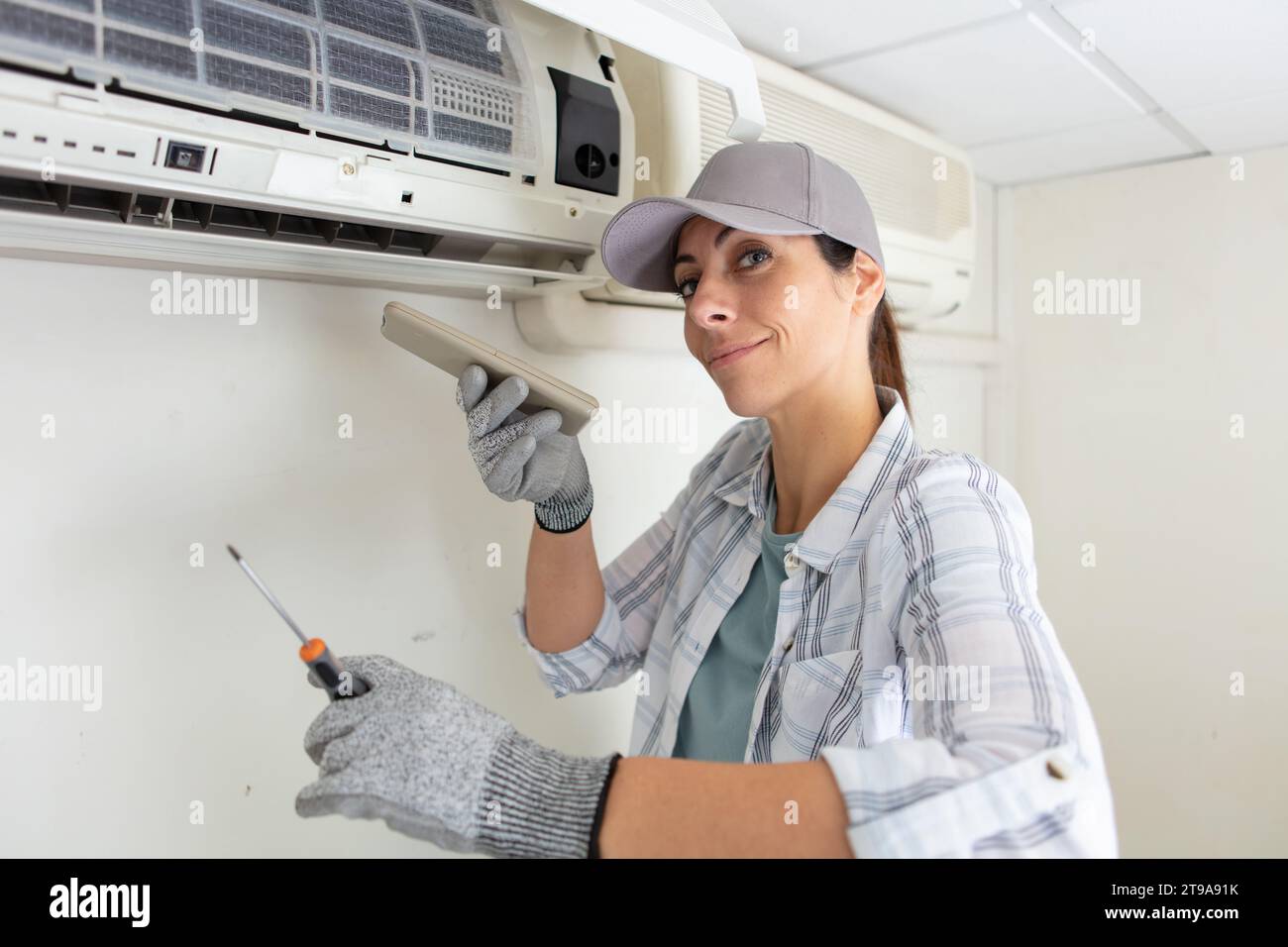 beautiful woman installing new ac system in office Stock Photo - Alamy