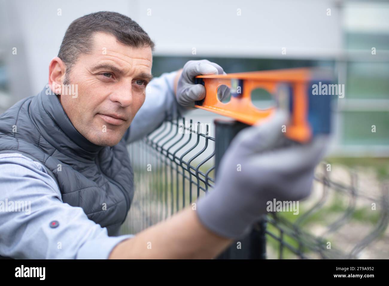 fence construction - worker check the level of metal post Stock Photo ...