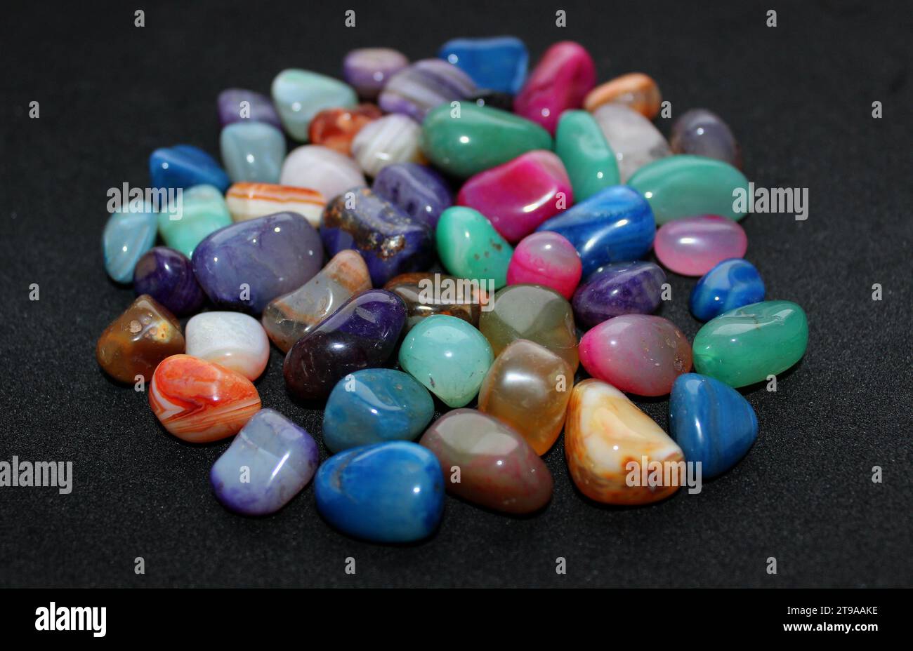 Colored rough gemstones in a heap of black surface detailed angle view ...
