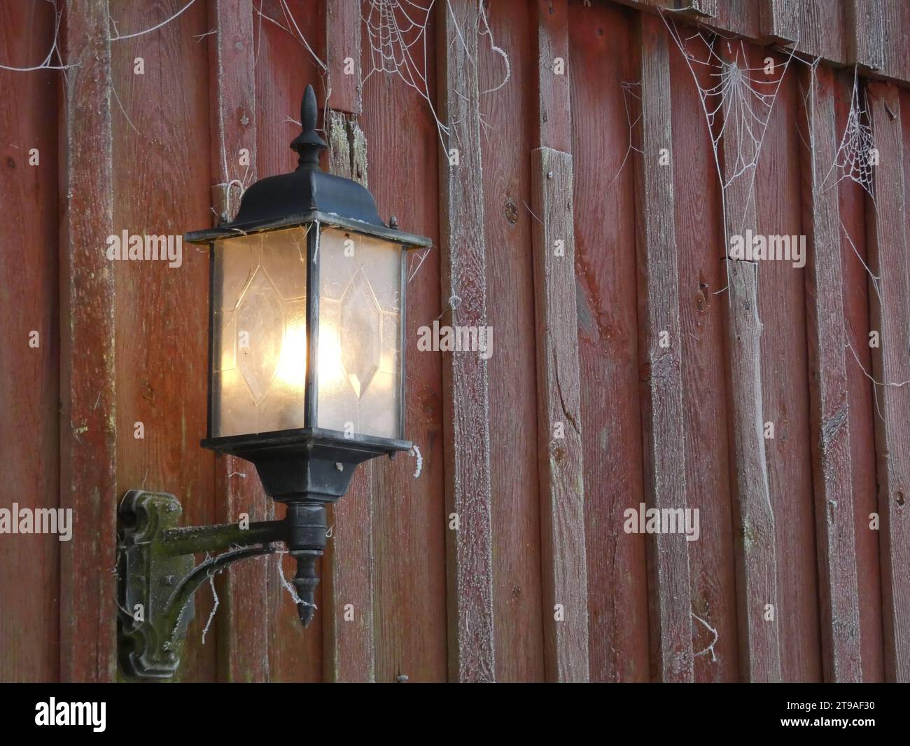 A close-up view of a wall-mounted light fixture against a brown-painted ...