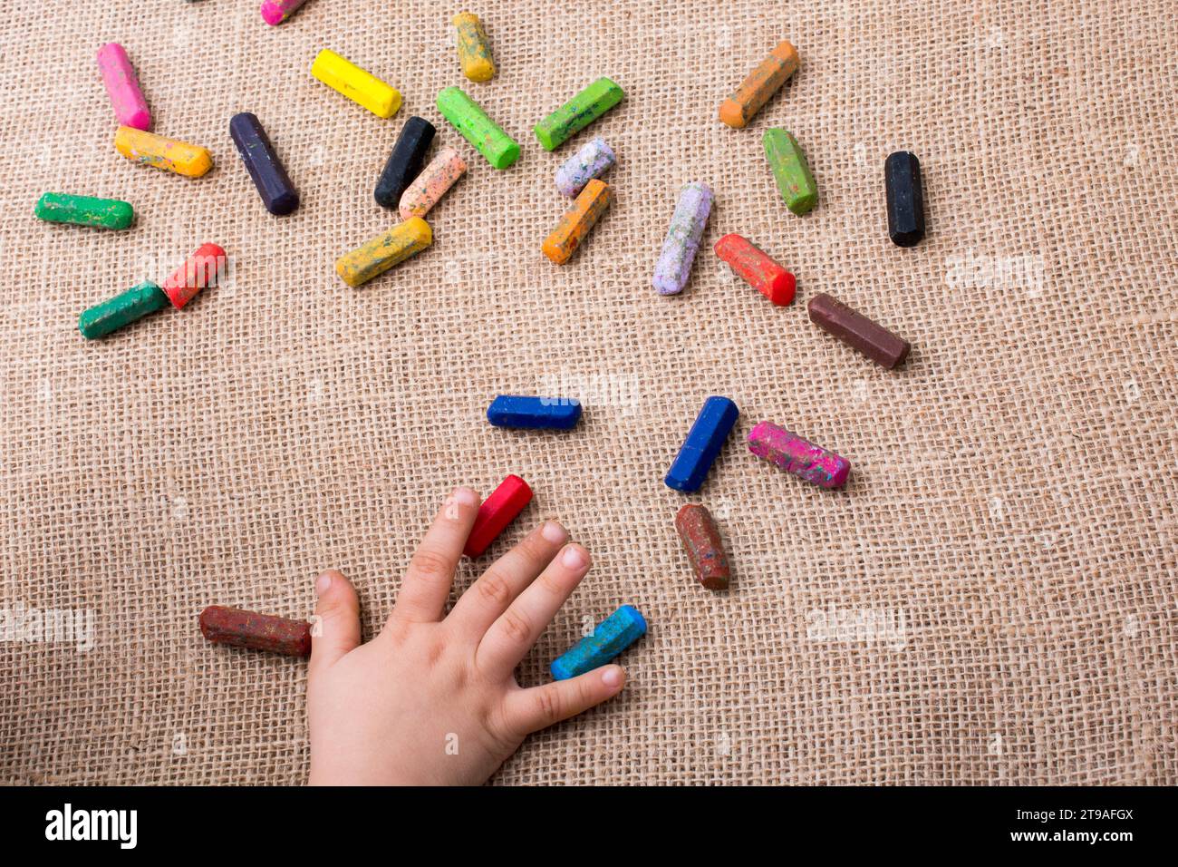 Used color crayons and a toddlers hand holding one Stock Photo - Alamy