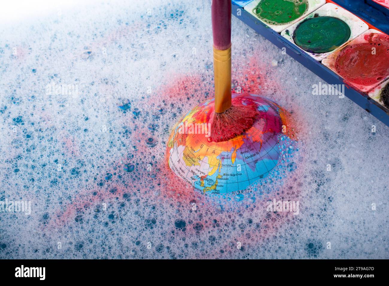 Paint dissolving through painting brush on the top of globe Stock Photo ...