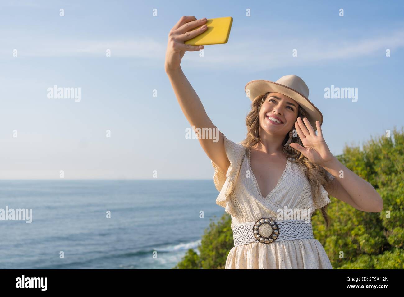 Horizontal photo of a blonde beauty woman in summer clothes waving ...