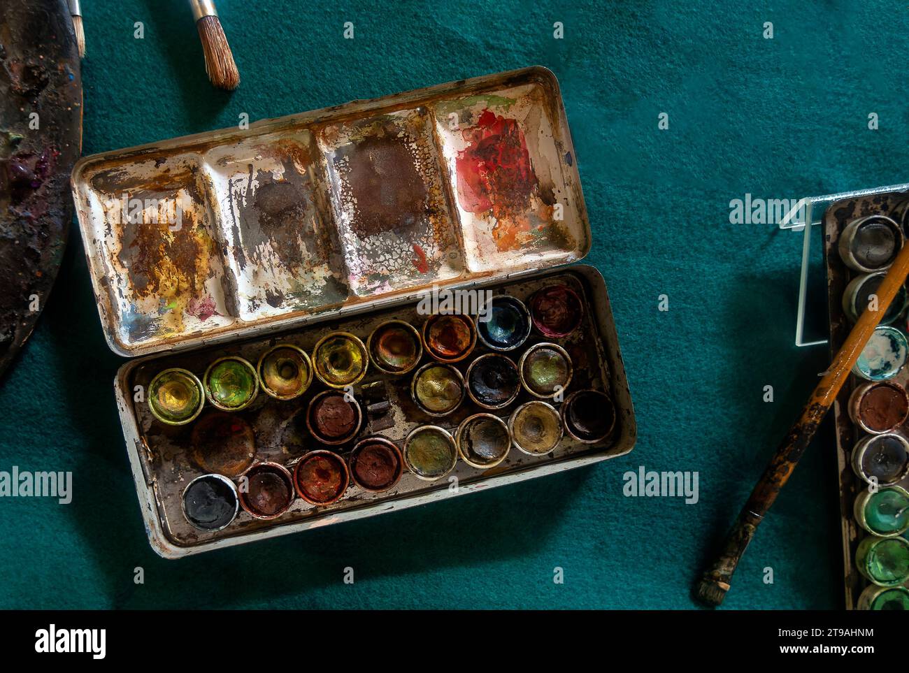 A Palette of old mixed paints with a brush lies on an old green cloth ...