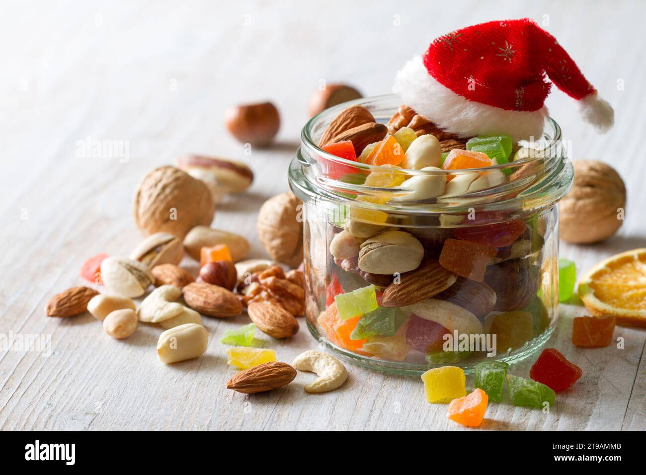 Christmas mix of nuts and candied fruits in glass jar with Santa hat on ...