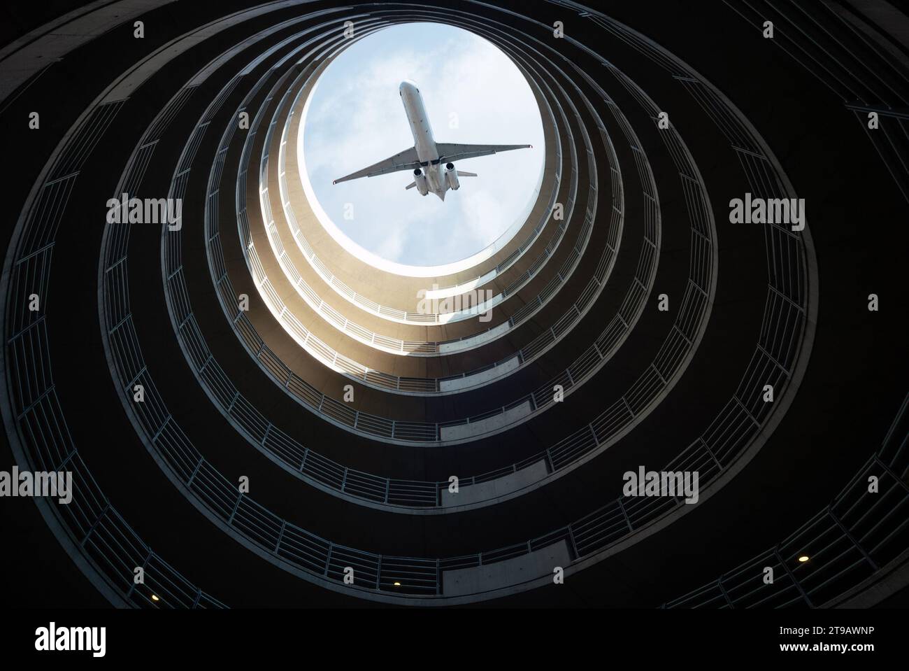 A plane takes off above the modern architecture of a circular parking ...