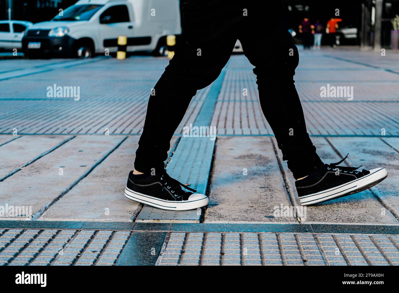 Young man walking down the sidewalk in a city. Lateral View Stock Photo ...