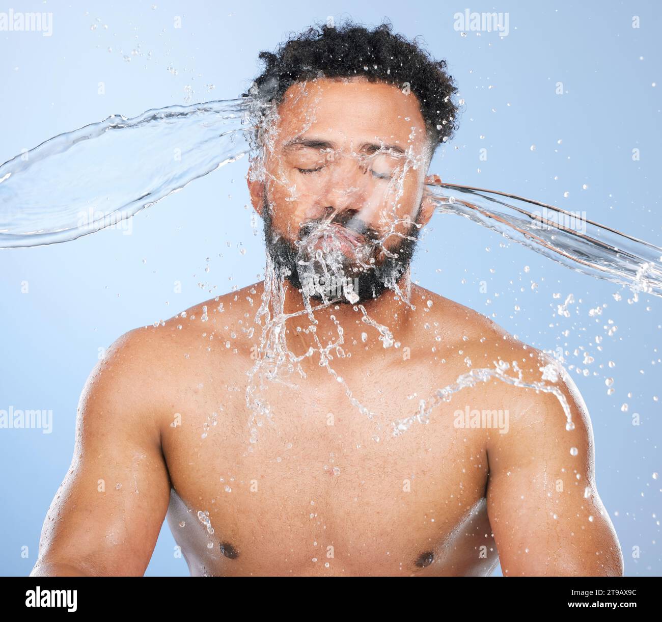 Black man, water splash and washing in skincare for cleaning, hygiene or grooming against a blue ...