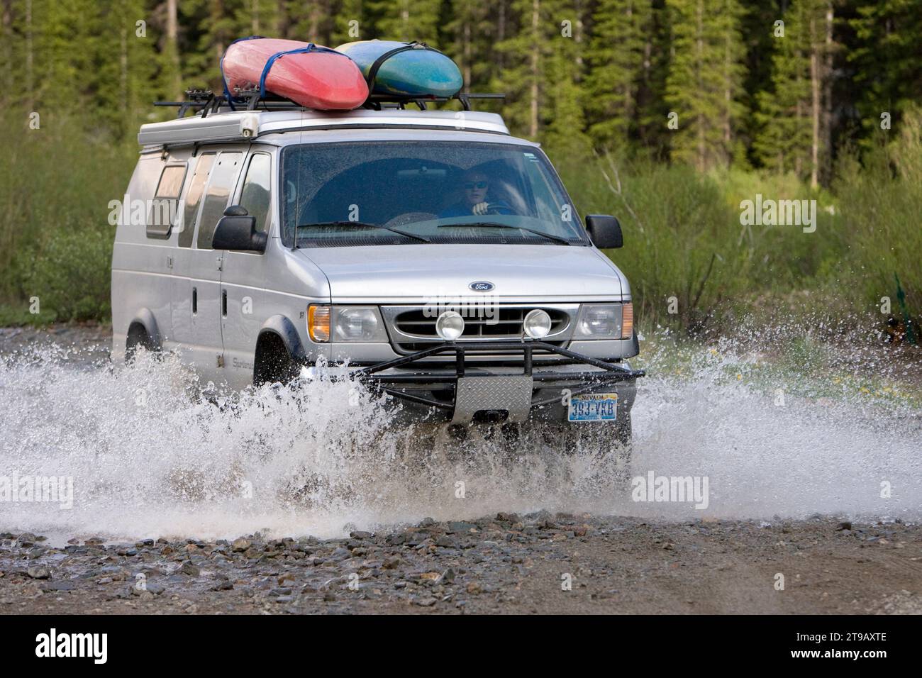 Big 4-wheel drive van charging through mud with kayaks on top Stock ...