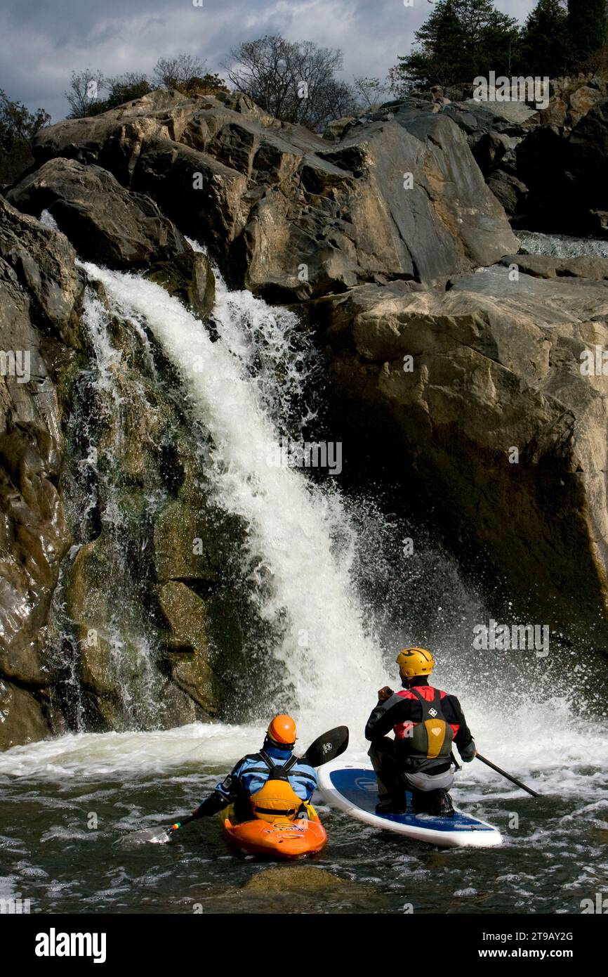 A male kayaker and a male stand up paddleboarder hanging out at the ...