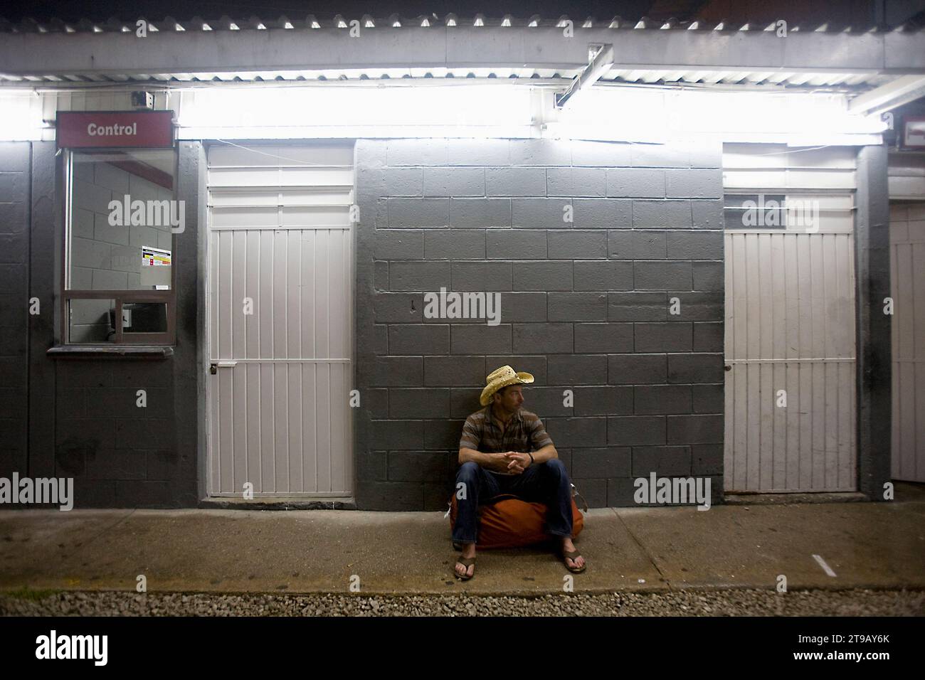 One male traveler sitting on his bag against a wall and waiting for a ...