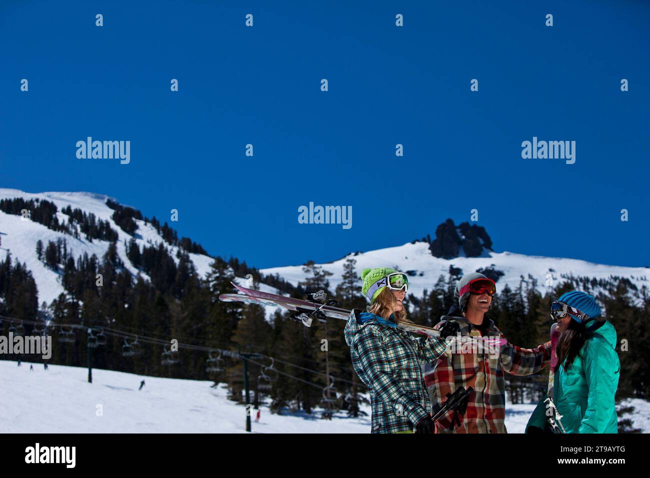 Three friends (one male and two females) hanging out with skis and a ...