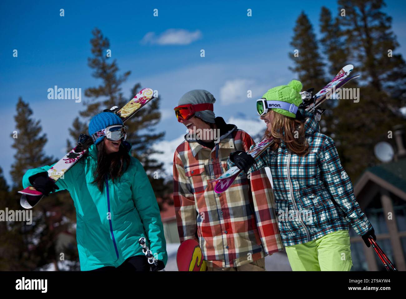 Three friends (one male and two females) hanging out with skis and a ...