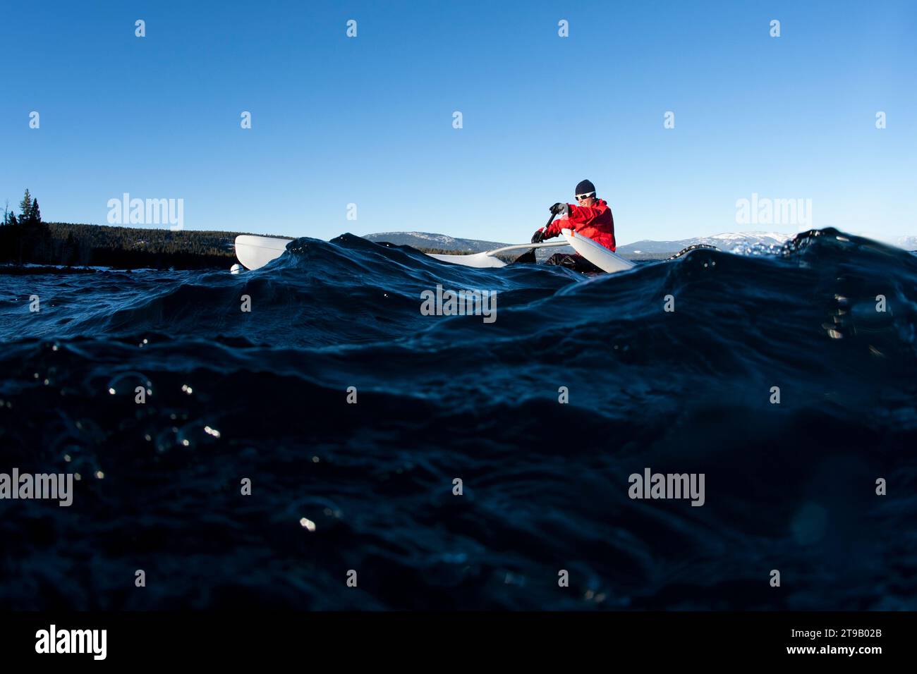 Low angle perspective of one man paddling his outrigger canoe on a ...