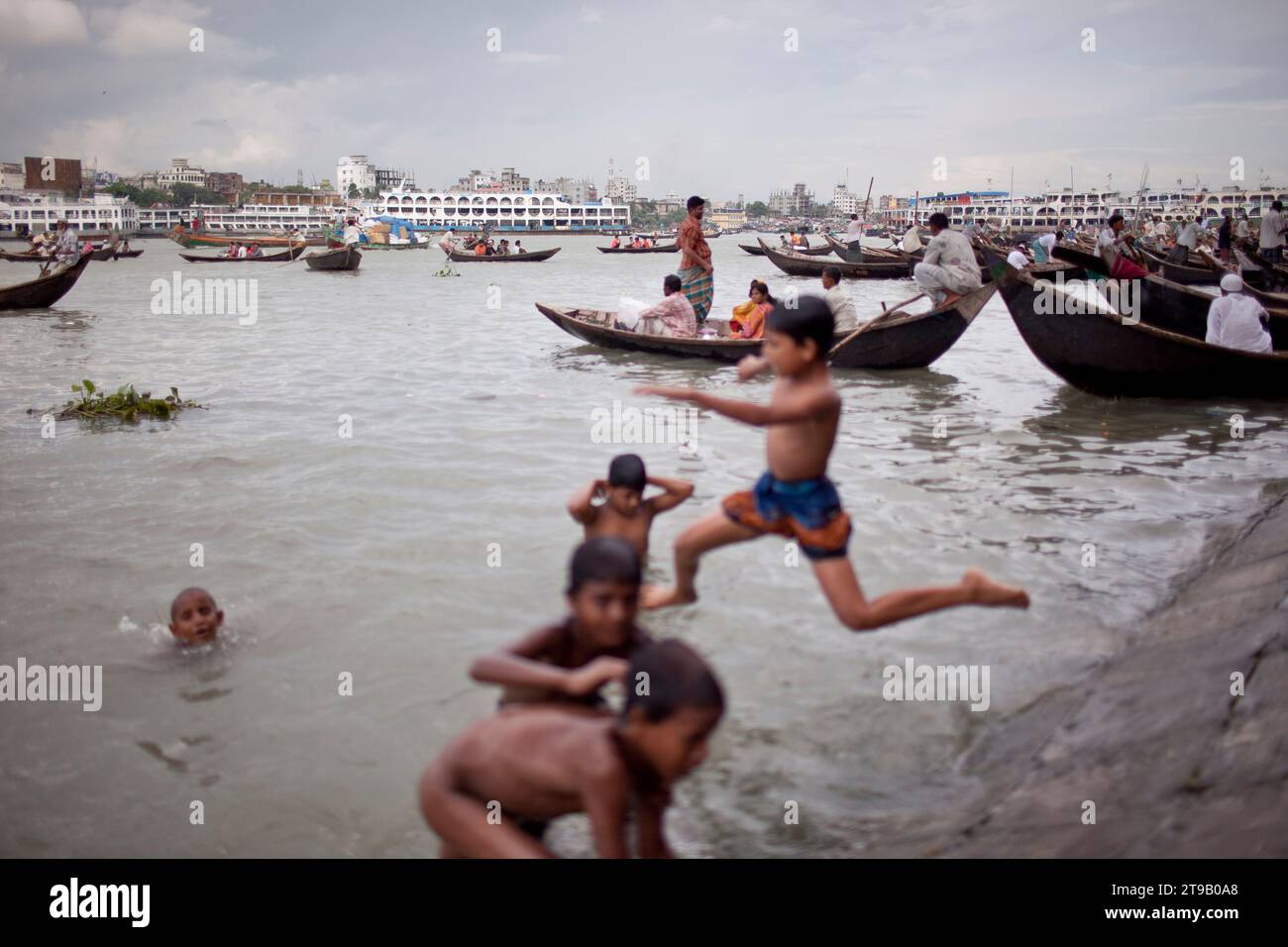 Dhaka, Bangladesh - August 2011: Young boys swimming in the busy Buriganga River (Old Ganges ...