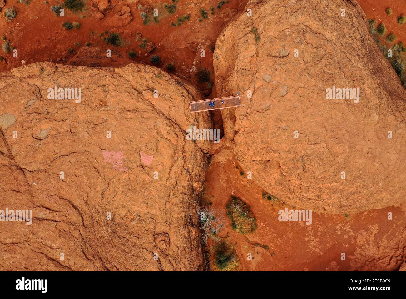 Two boys cross bridge between huge red rock boulders from drone Stock ...