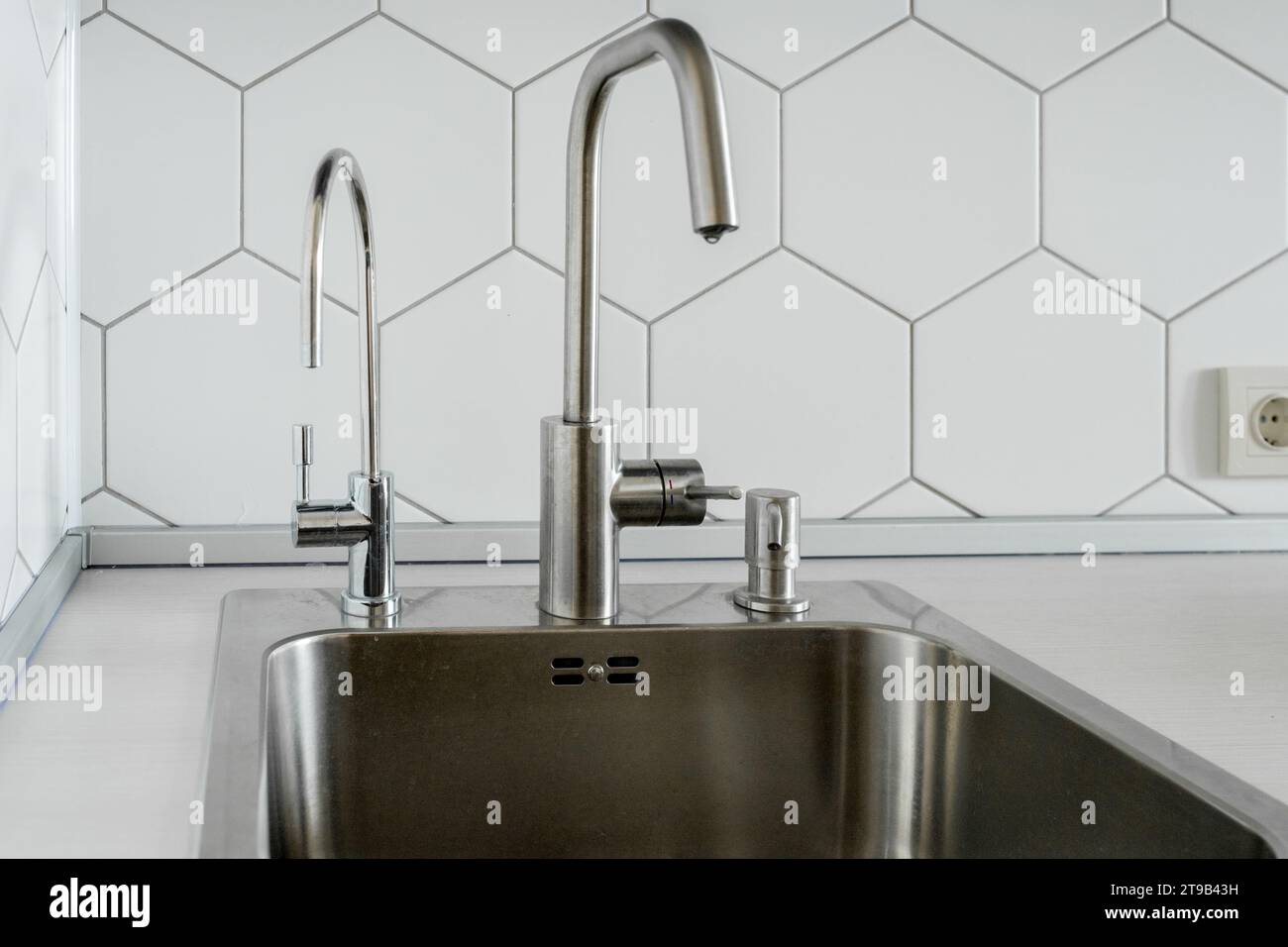 Modern kitchen, view of a metal sink with a water tap, a soap dispenser ...