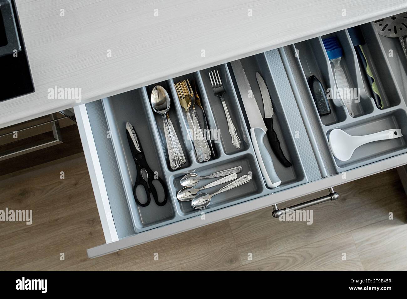Open drawer in a kitchen, which is part of a white kitchen cabinet and ...