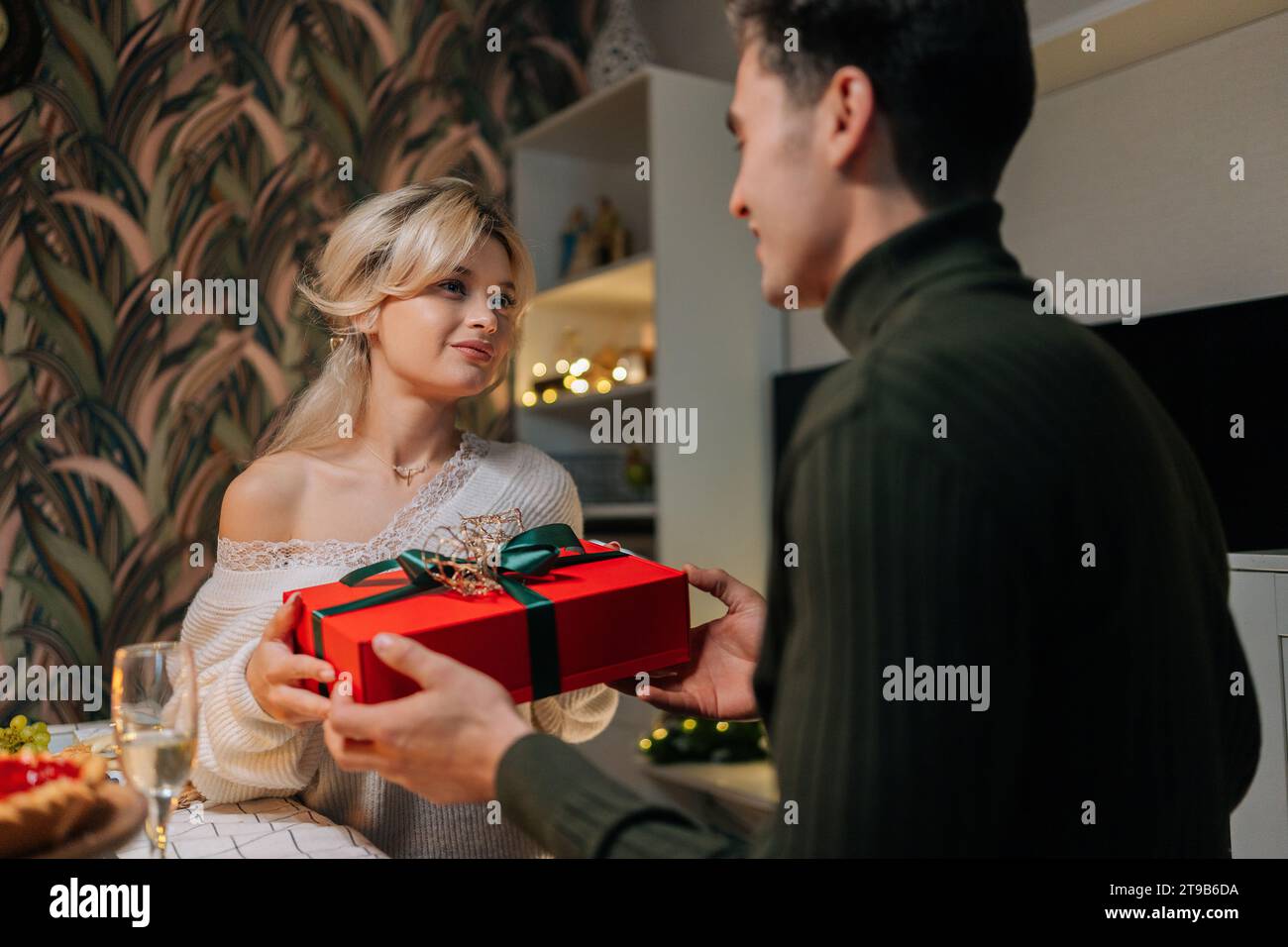 Rear view of loving man making surprise, giving gift box with present ...