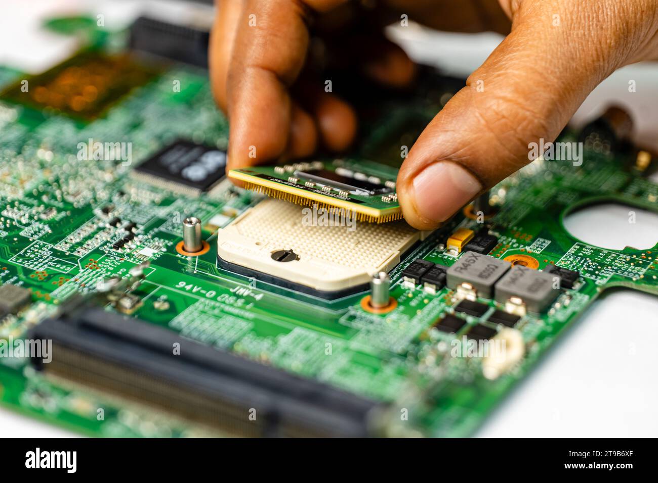 technician meticulously repairs a laptop motherboard using a variety of ...