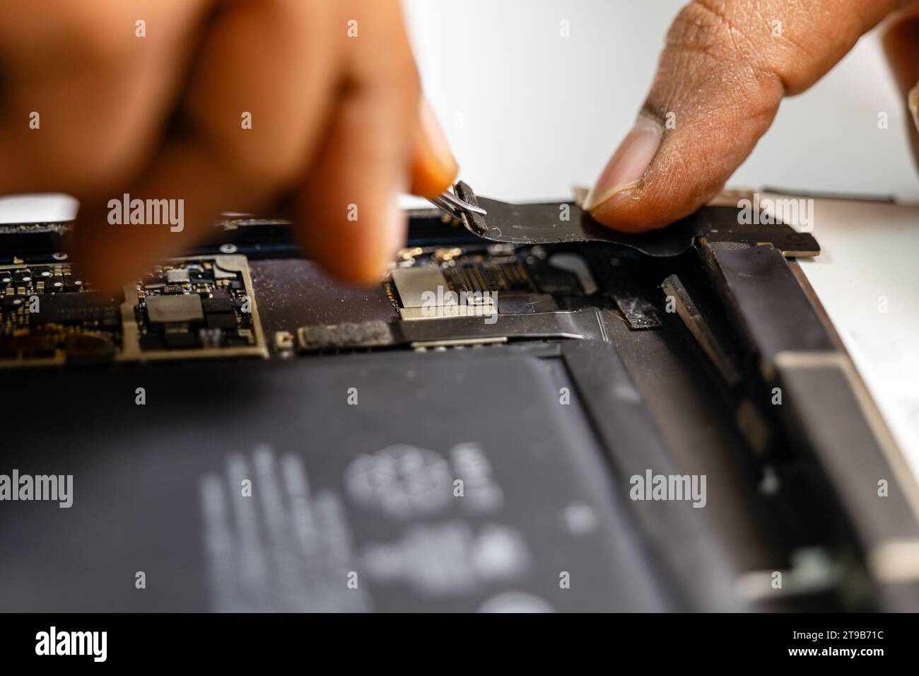 technician carefully removes the damaged ribbon from a tablet using ...