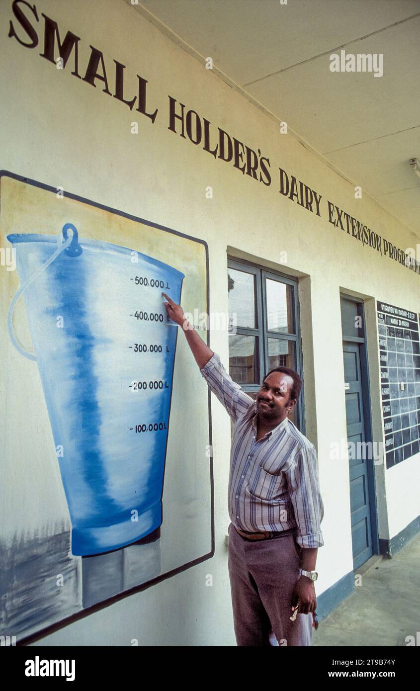 Tanzania, Tanga - Man pointing at mural showing target amount of milk ...