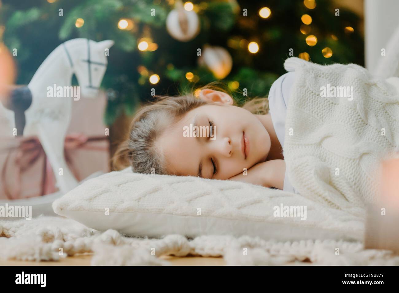 Sleeping child wrapped in a knit blanket with a serene expression, by a ...