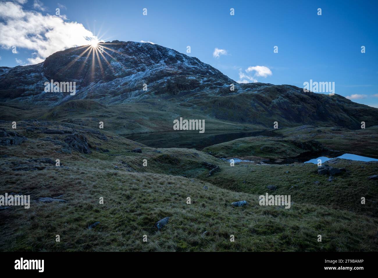 Sun peeping over the Mountain Great End and Sprinkling Tarn in the lake ...