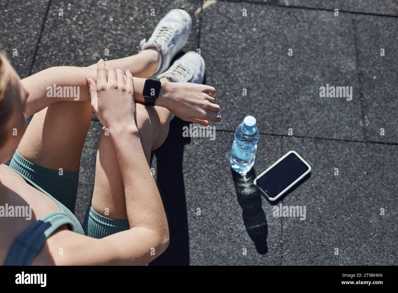 top view of fit woman in activewear checking fitness tracker next to ...