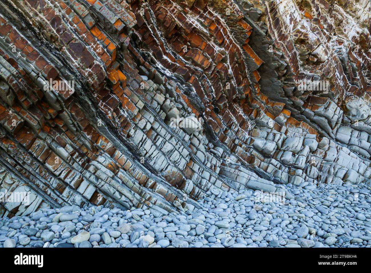 Stratigraphy of colored rocks of the cliff, and pebbles of the ...